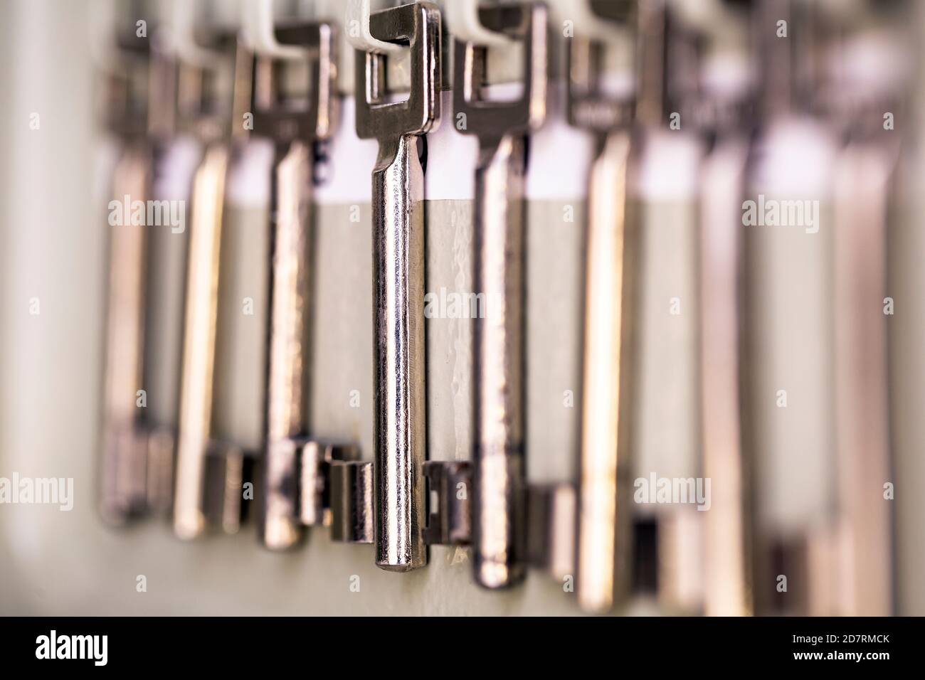 Row of old metal silver skeleton keys hanging in rack with numbers of ...