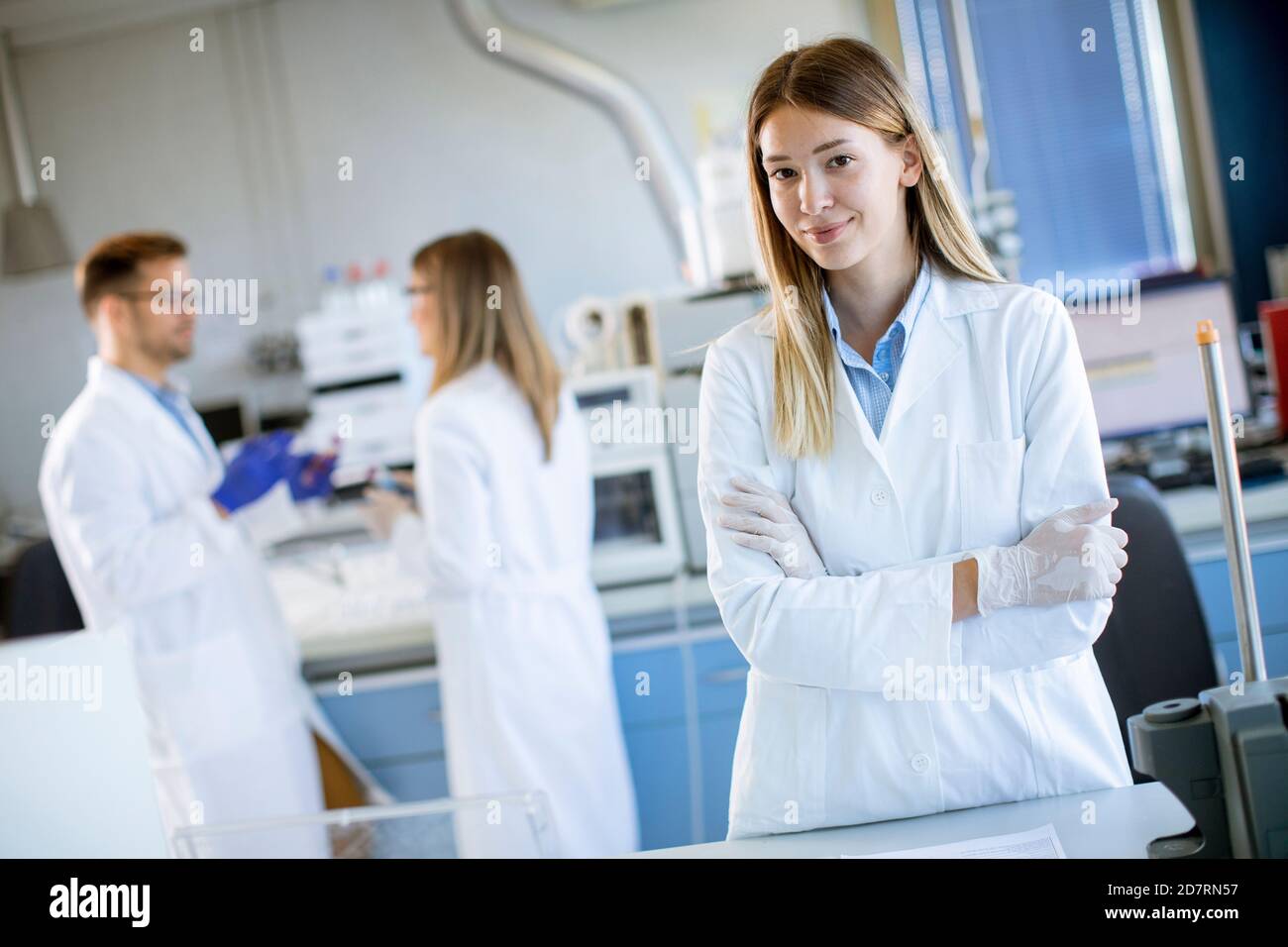 Young female scientist in white lab coat standing in the biomedical lab ...