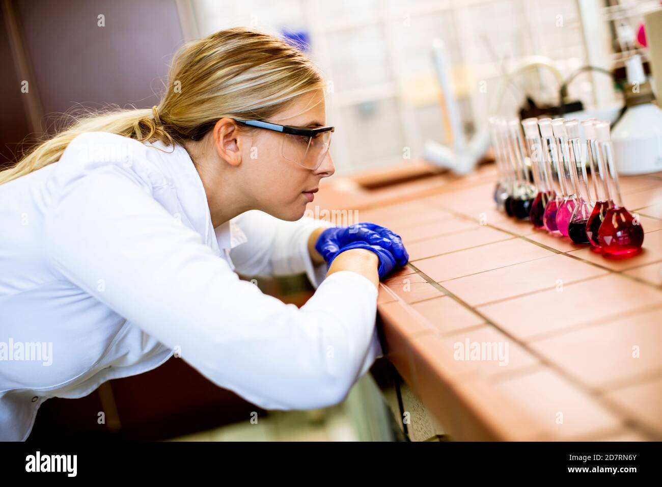 Young female scientist in white lab coat analyzing liquid samples the ...