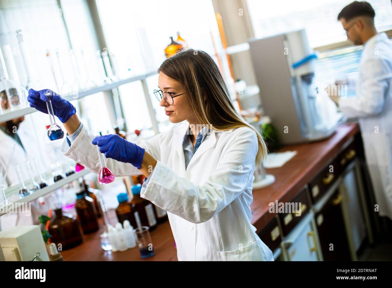 Pretty young female scientist examining liquid in biochemical lab Stock ...