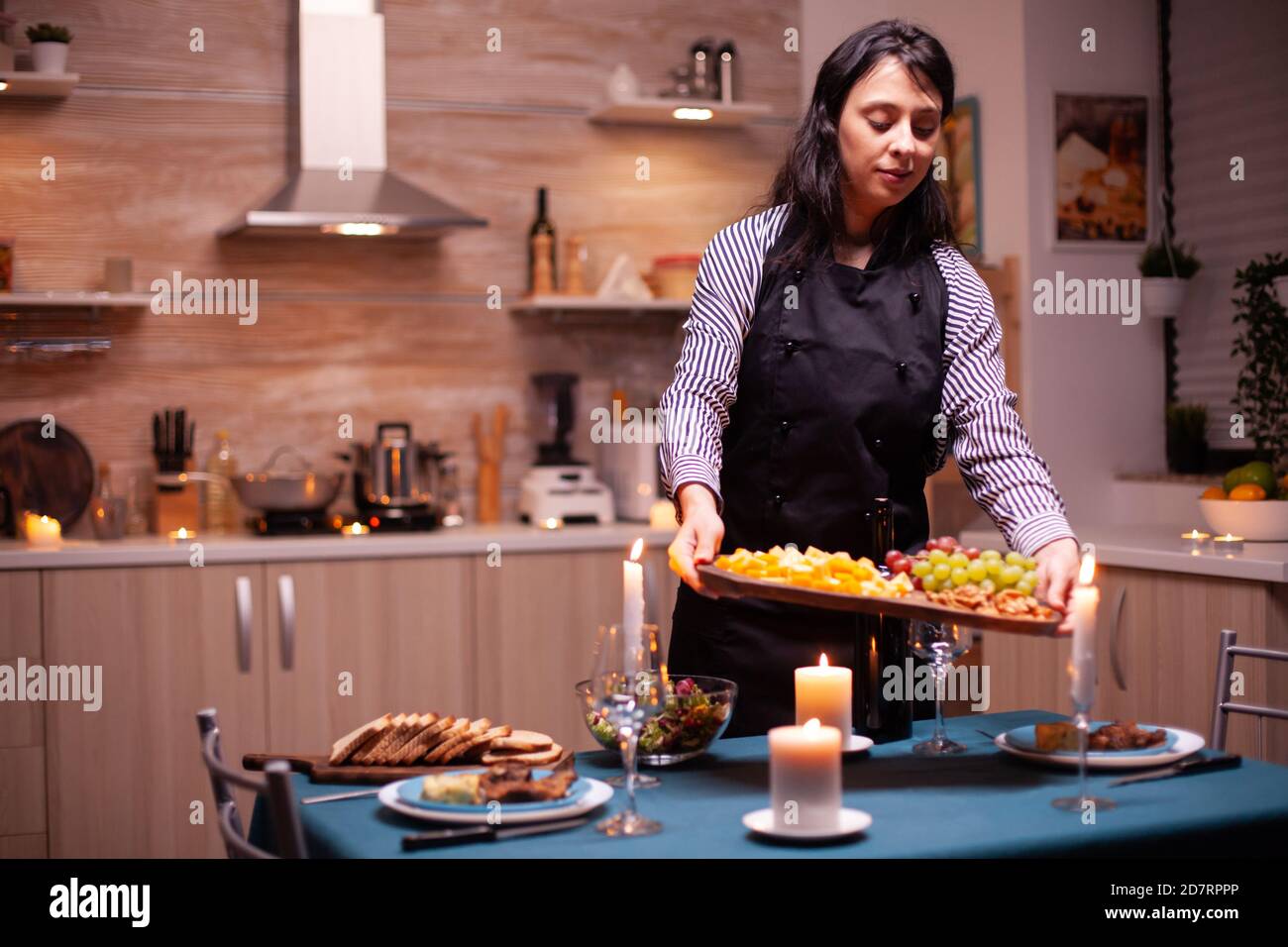 Happy wife preparing romantic dinner and holding board with grapes and ...