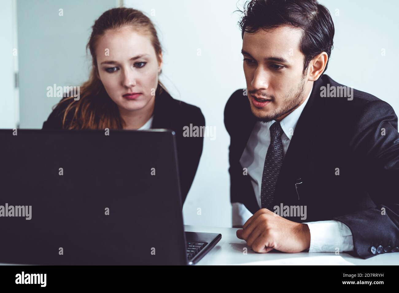 Unhappy serious businessman and businesswoman working using laptop ...