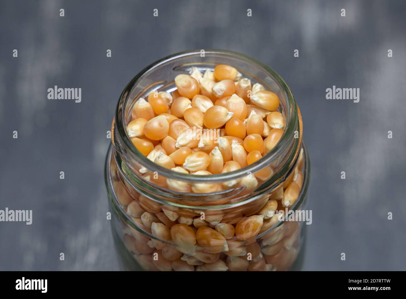 Close up of a glass jar full of corn grains placed on a tabletop. Eco ...