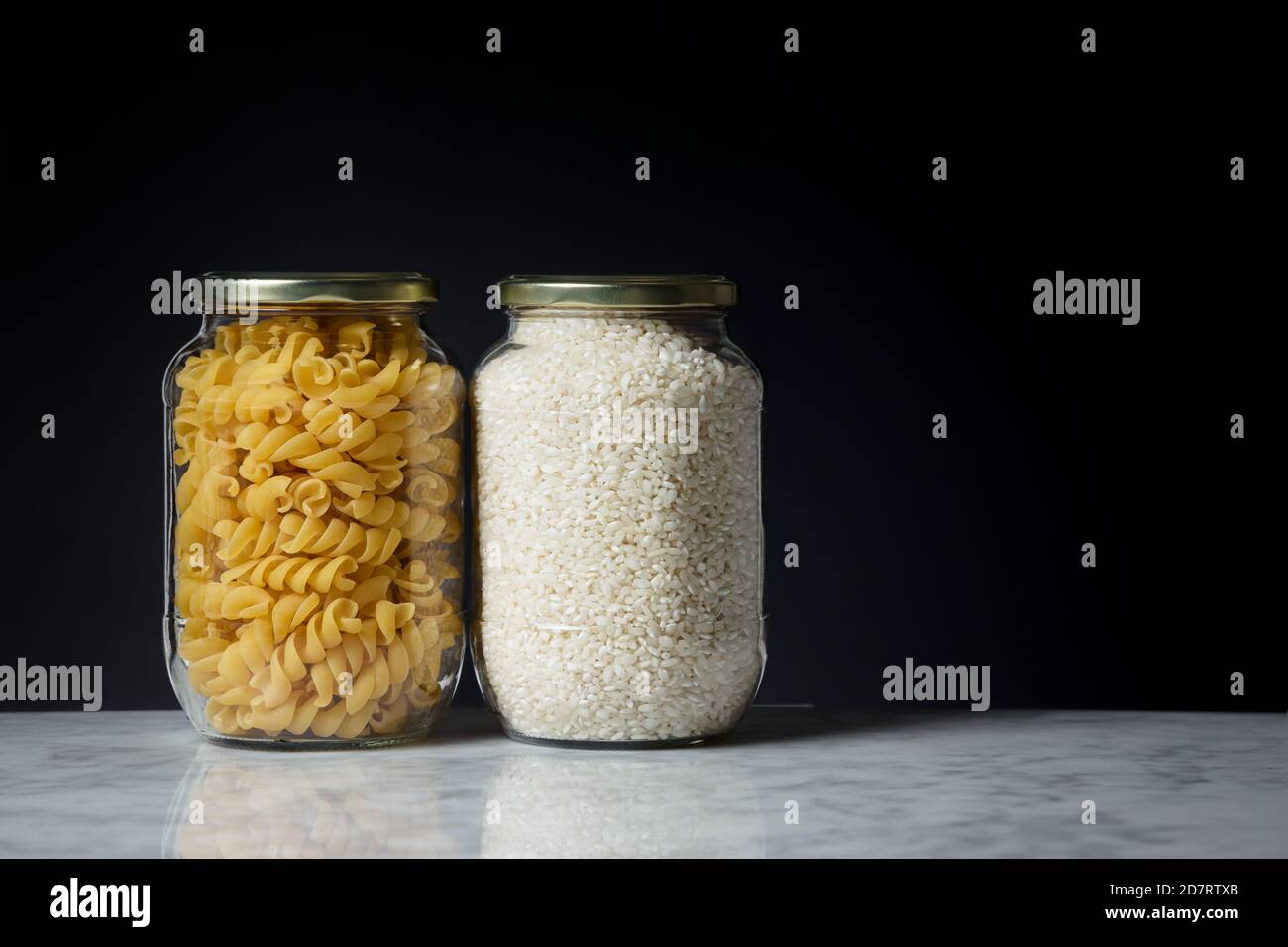 Set of glass jars with pasta and rice placed on a marble tabletop. Zero ...