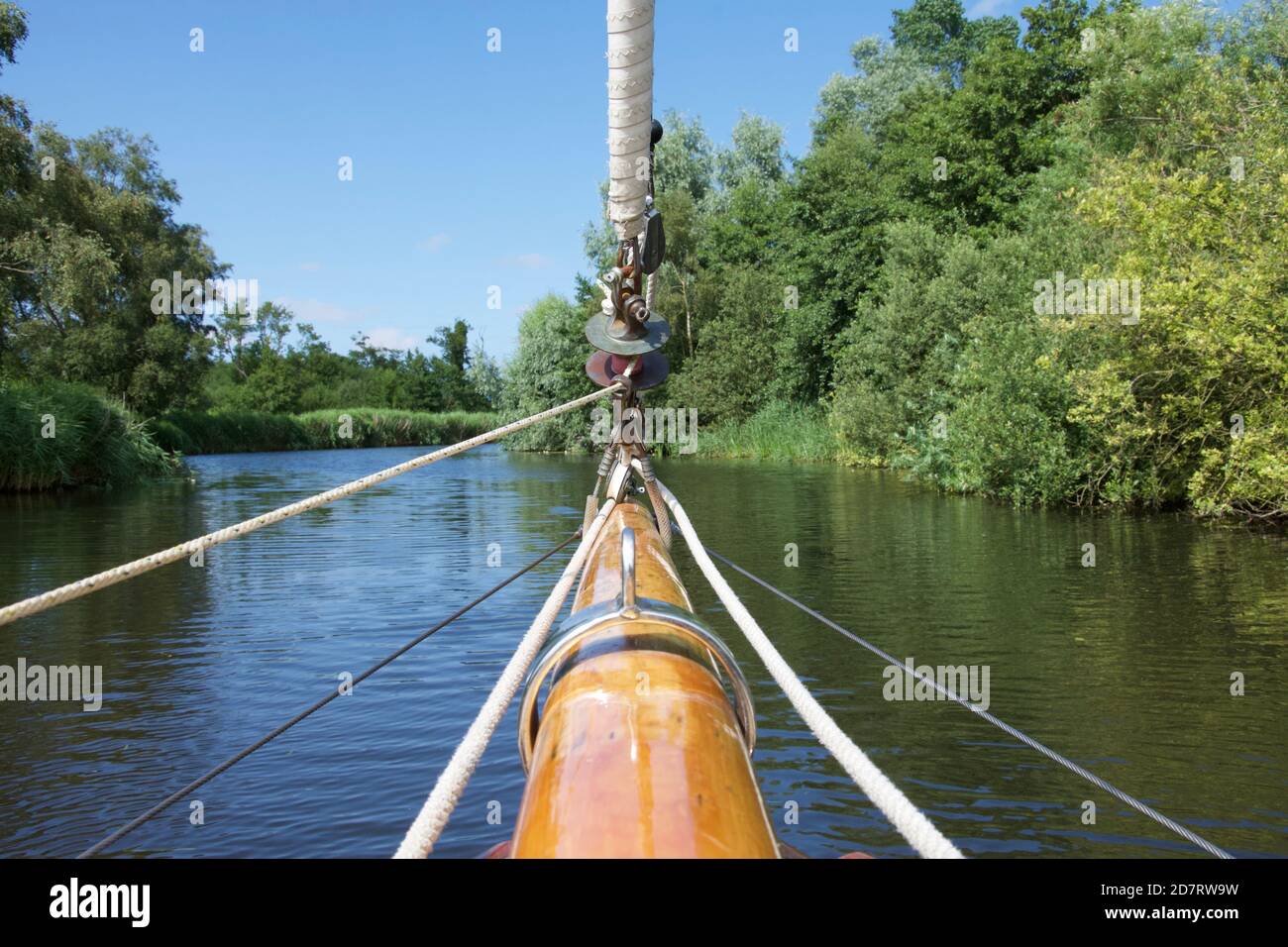 The wooden bowsprit and furled jib of a sailing yacht, moving up the ...