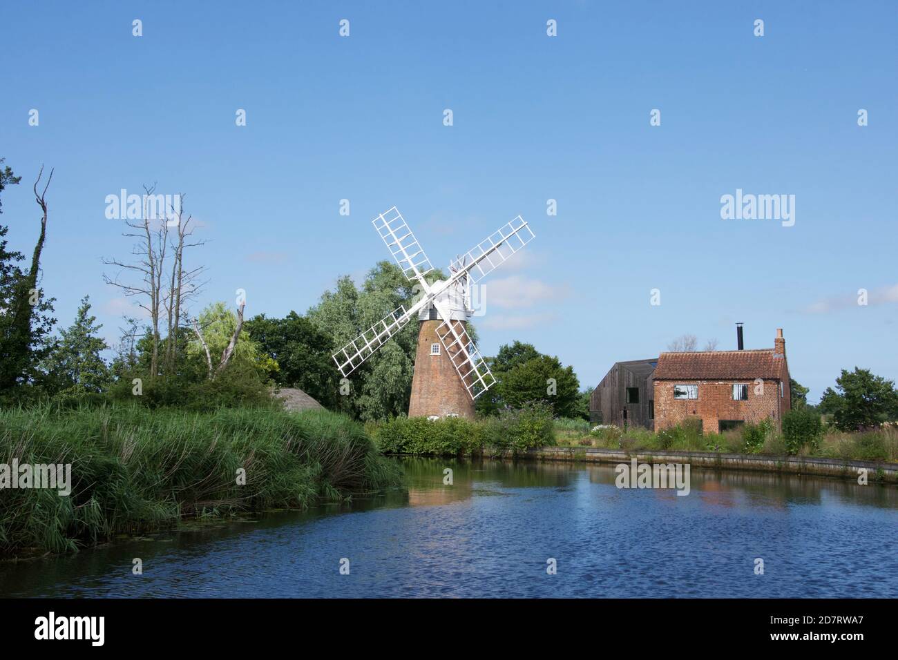 A traditional windmill (wind pump) next to a pretty cottage or house on ...