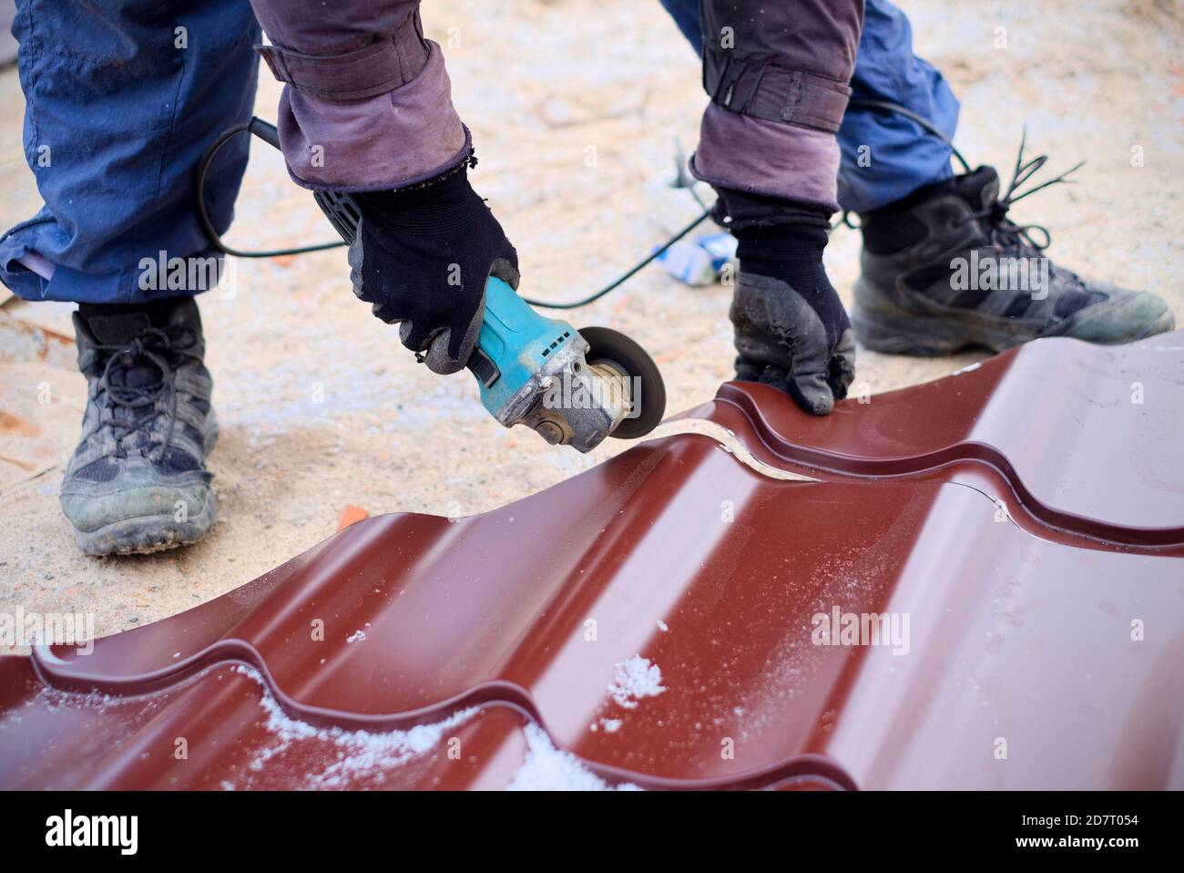 Worker use grinding machine for cutting metal roof sheets. A roofer ...