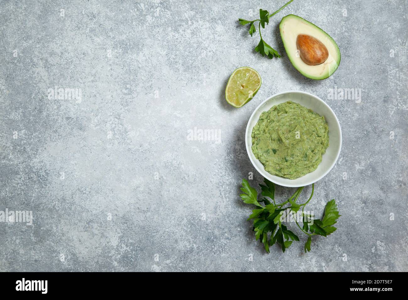 guacomole in a white bowl, fresh avocado on a gray concrete background ...