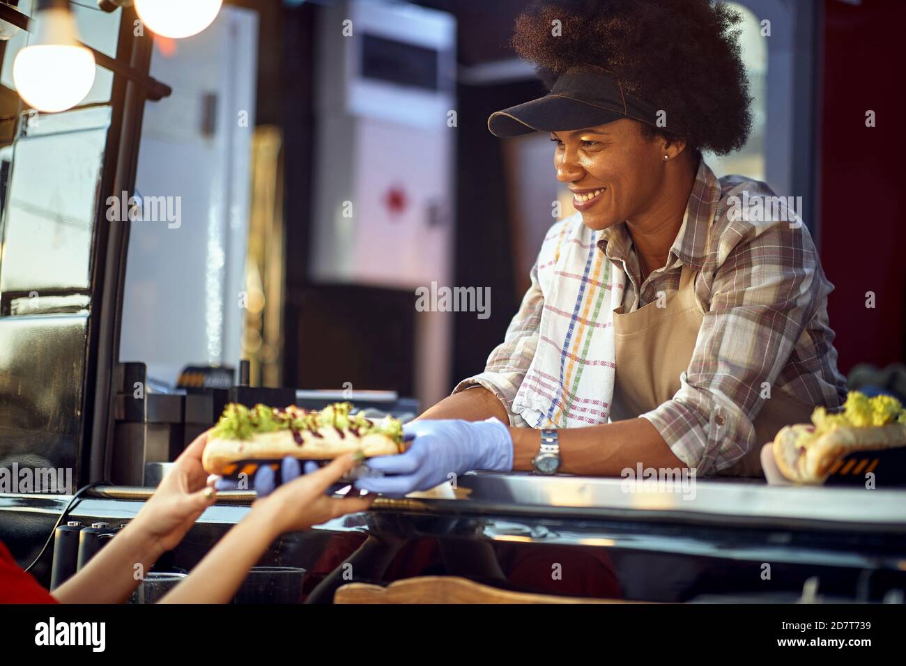 young afro-american female employee in fast food service giving ...
