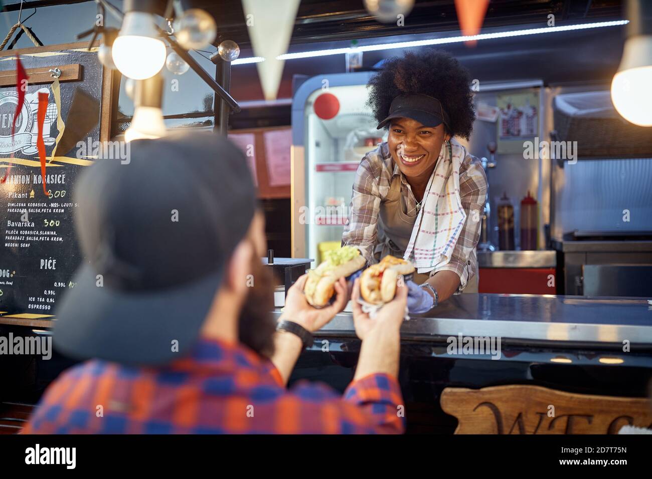 beautiful young afro-american employee giving with smile sandwiches ...