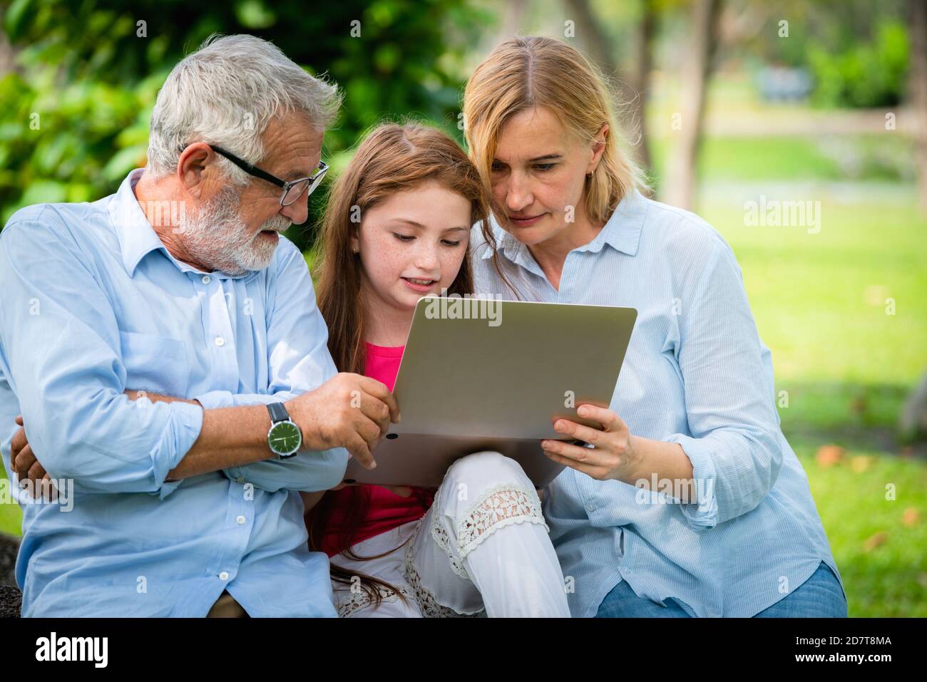 Happy family using laptop computer together in the garden park in ...