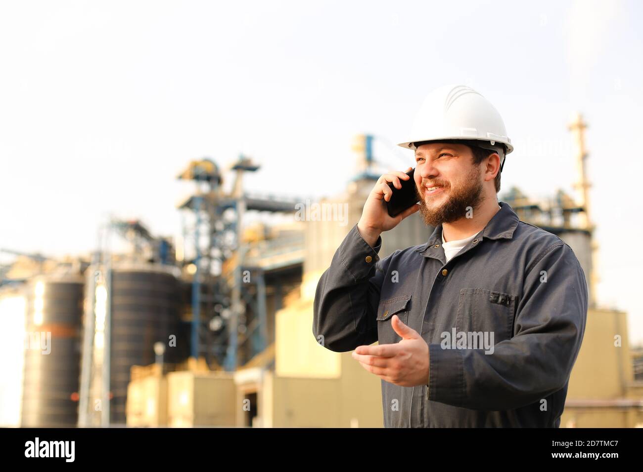 Portrait of industrial worker talking by VHF walkie talkie near factory ...