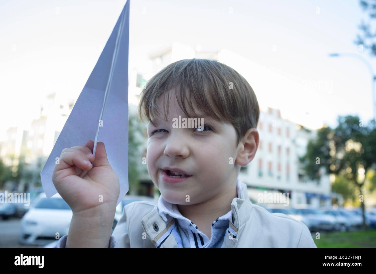 Child boy playing with paper airplane at urban park. Selective focus ...