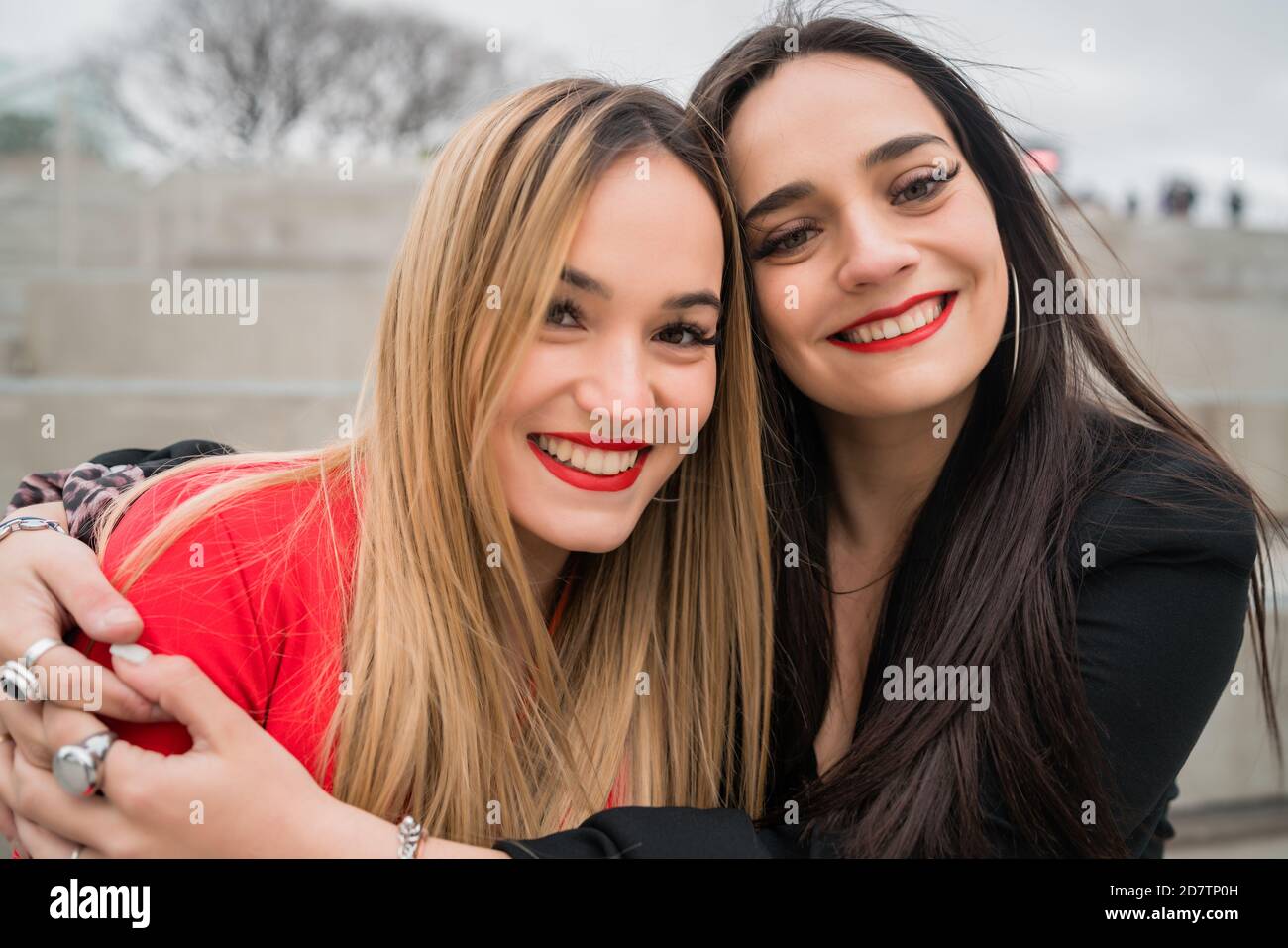 Portrait of two young friends hugging each other outdoors at the street ...