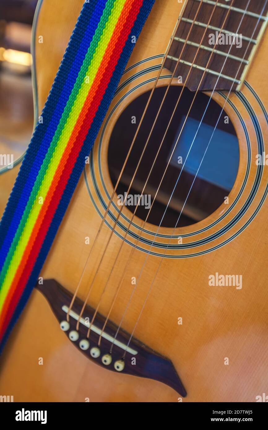 Vertical shot of an acoustic guitar with a rainbow strap under the ...