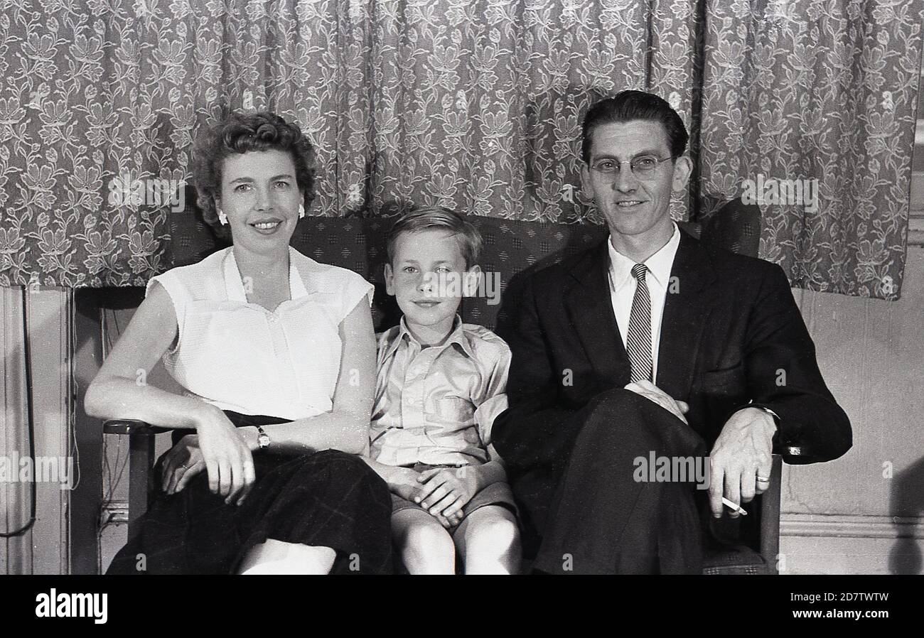 1950s, historical, family picture of a mother, father and son sitting together on a lounge chair ...