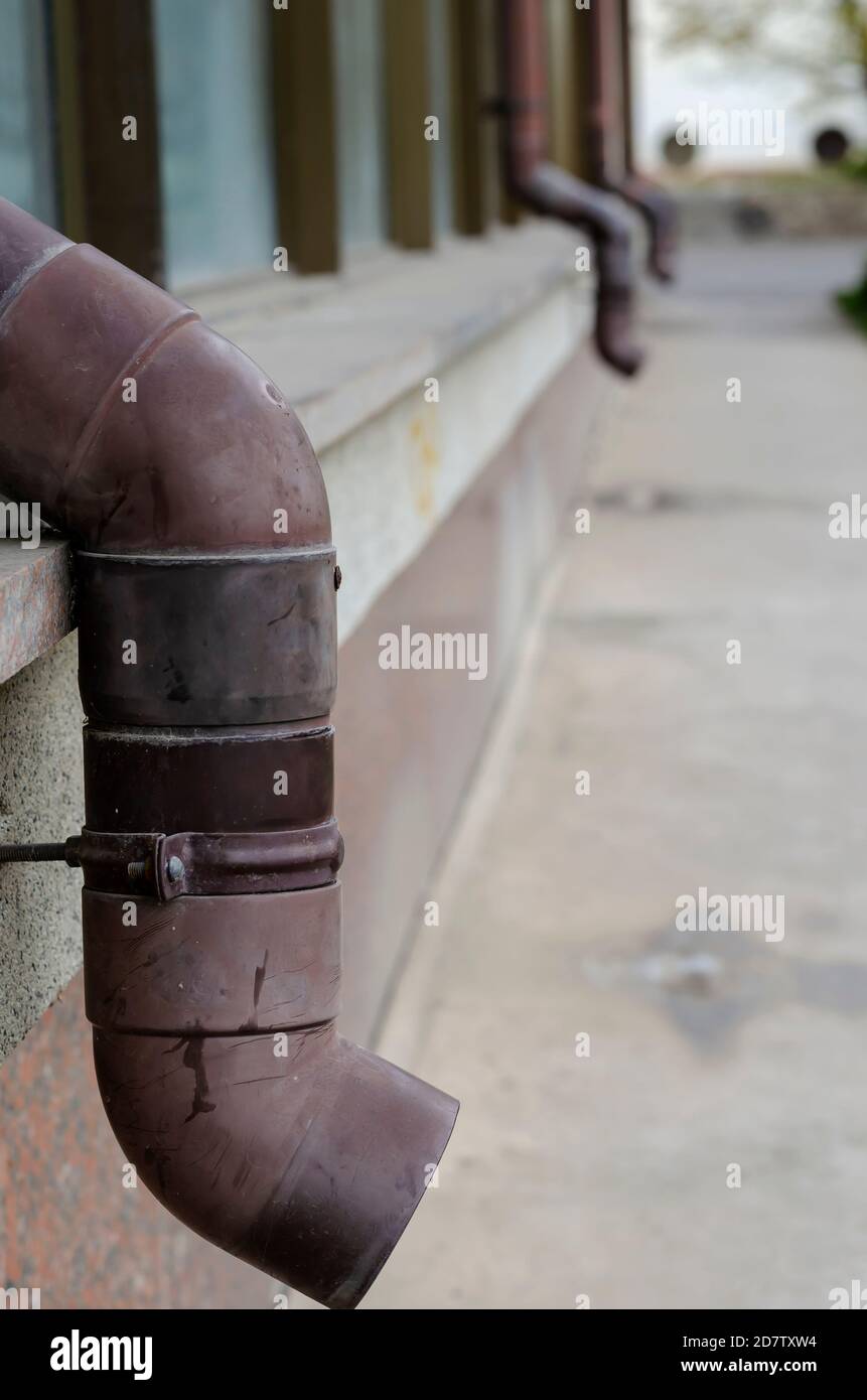 Facade of building with attached brown gutters. Row of plastic rain ...
