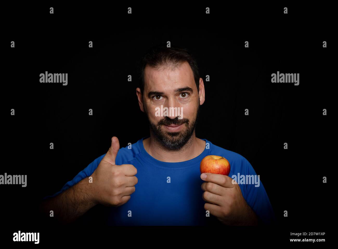 Bearded man dressed in blue t-shirt and holding an apple posing on ...