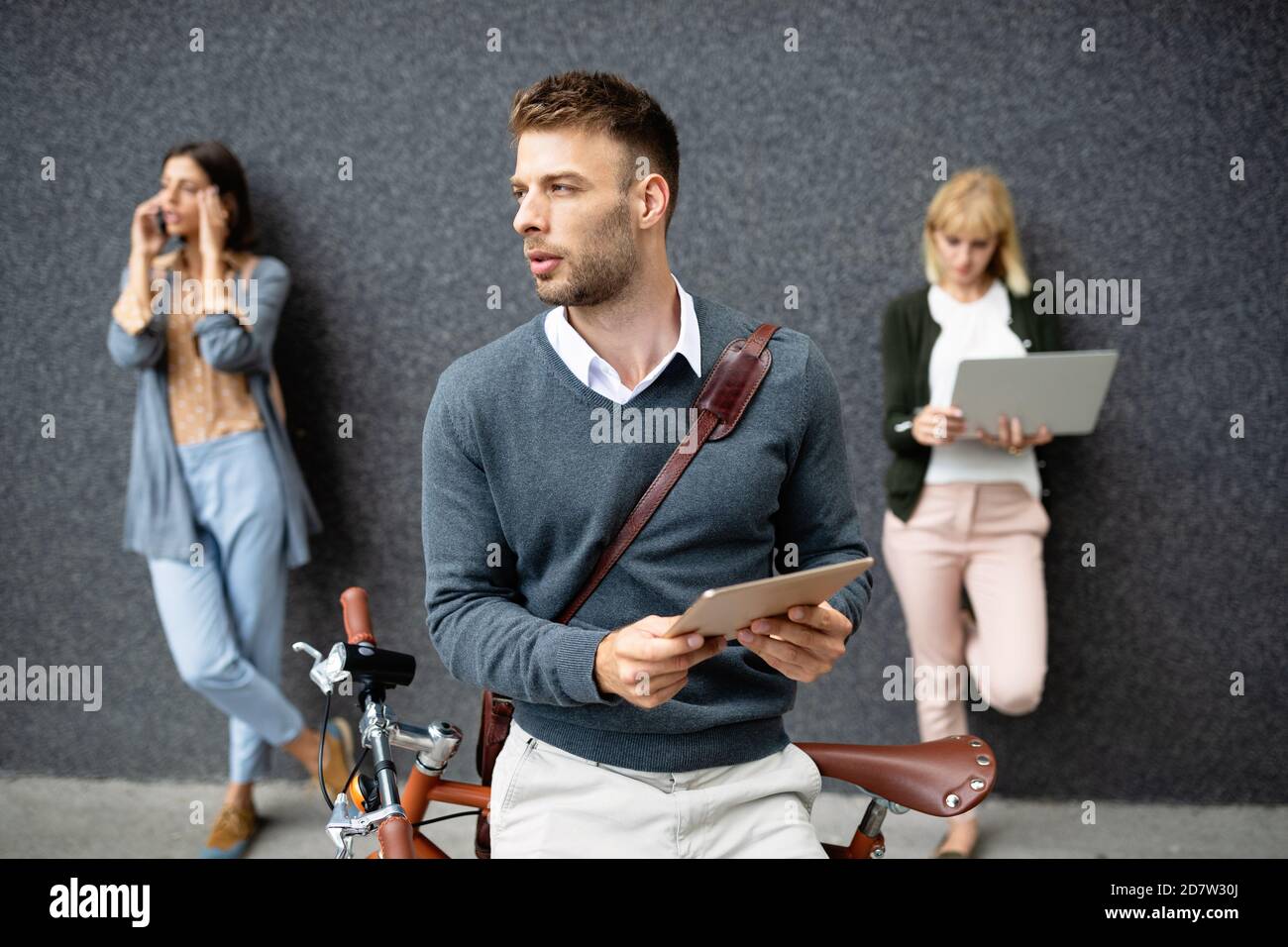 Group of young business people holding different digital devices ...