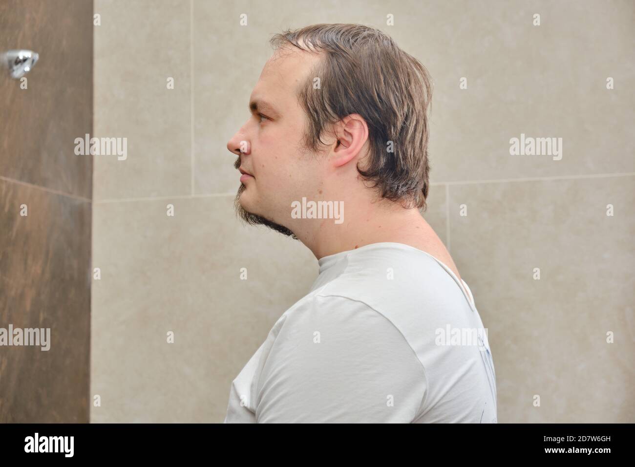 Portrait of a man in a white t-shirt with a half-shaved beard, face ...