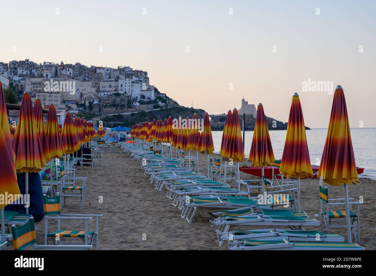 Colorful parasols on sandy beach of medieval small touristic coastal ...