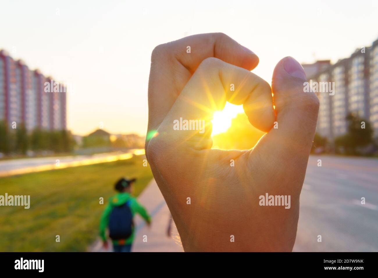 human hand covers the sunlight, the sun shines through the hand. urban ...