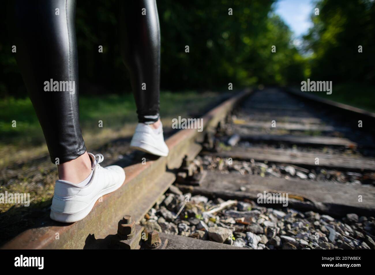 Railway tracks and rusty rails. Shapely slim legs of a young girl ...