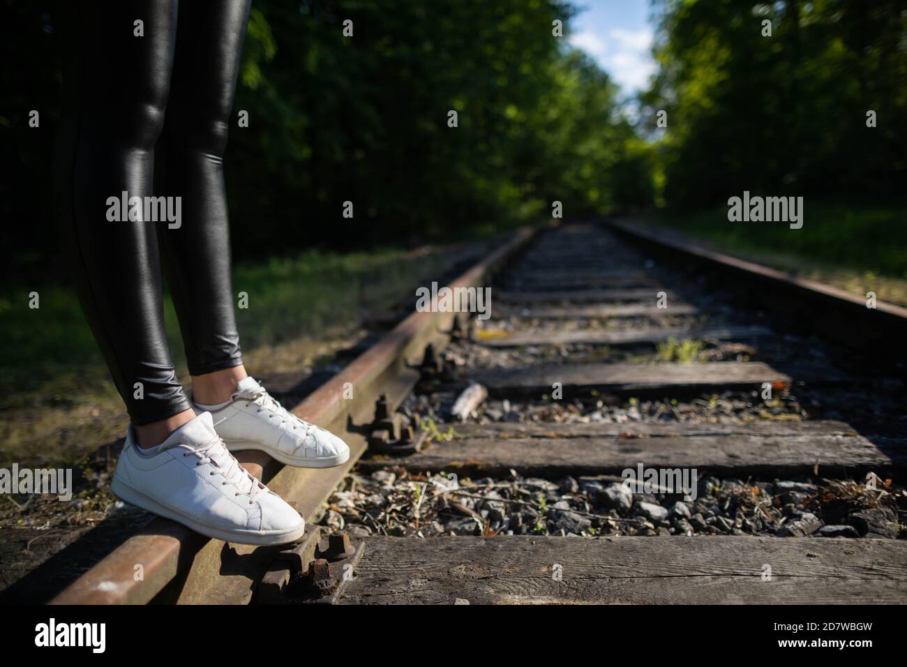 Railway tracks and rusty rails. Shapely slim legs of a young girl ...
