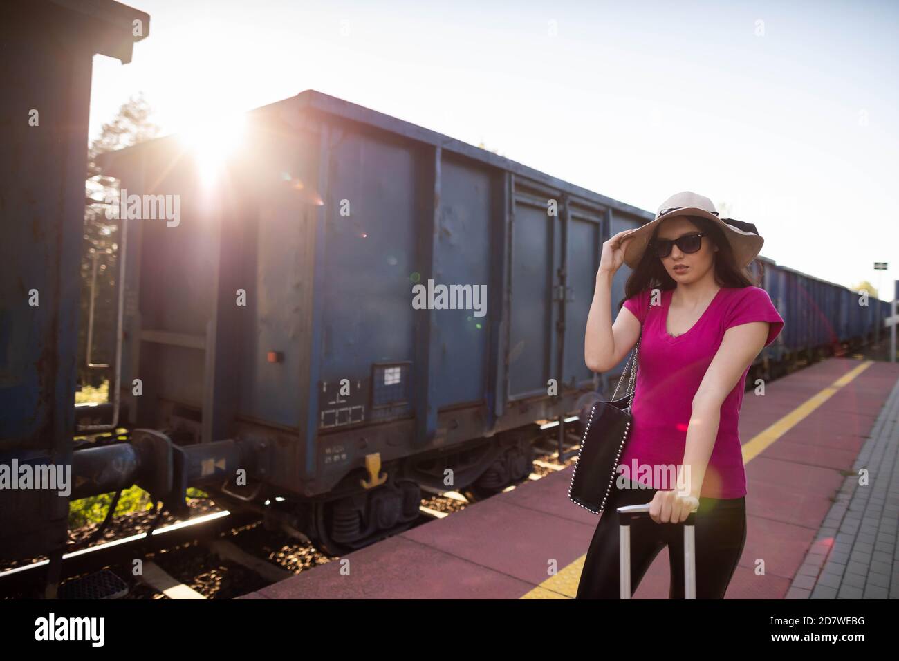 A freight train passes over the platform on which a young adult is ...