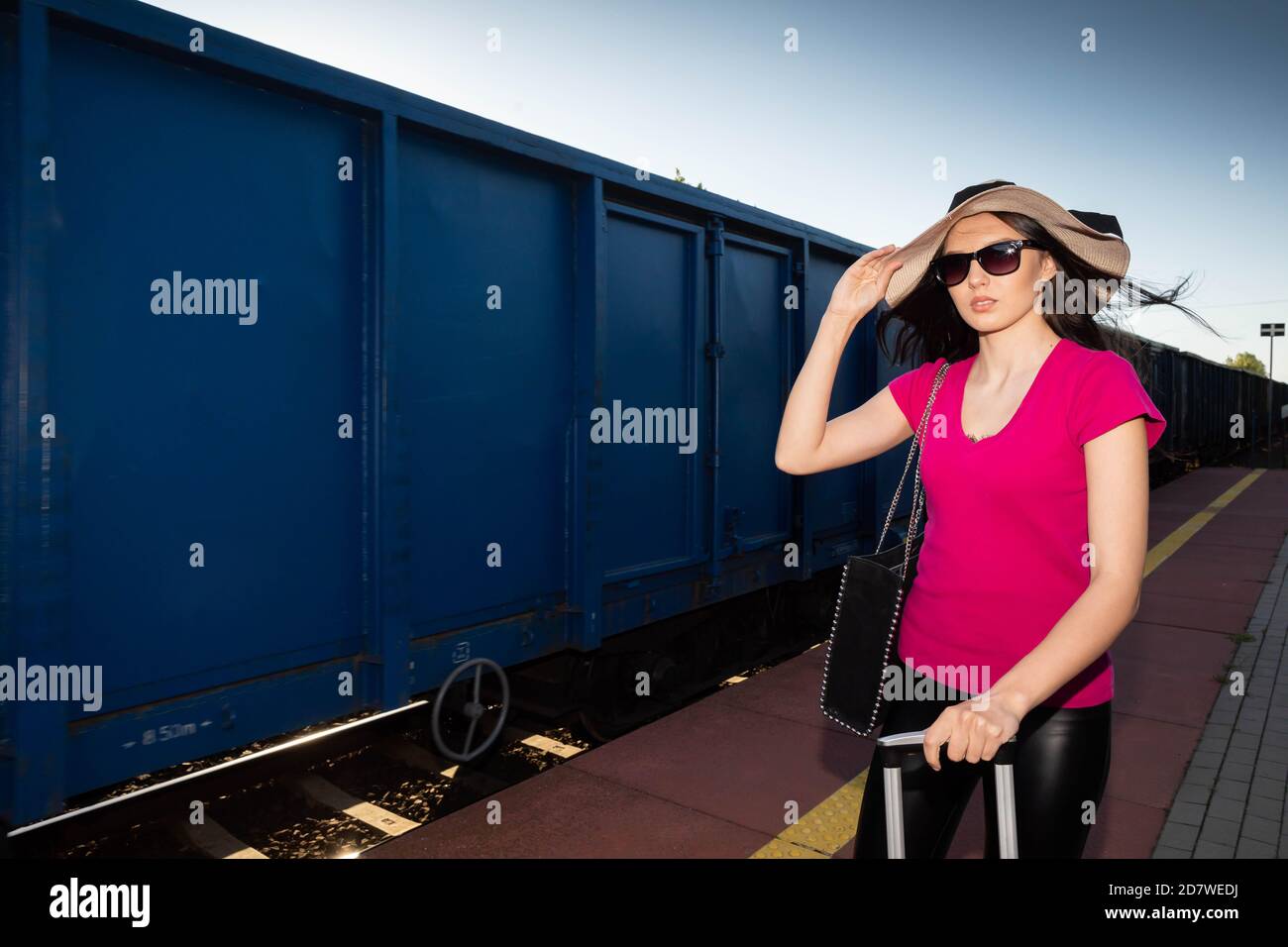 A freight train passes over the platform on which a young adult is ...