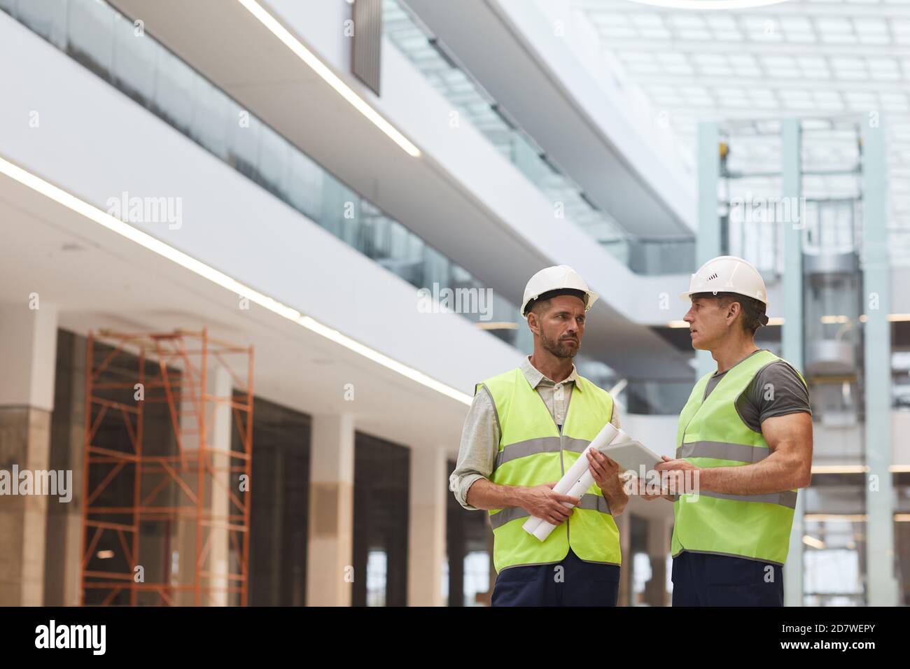 Portrait of two mature building contractors discussing work while ...