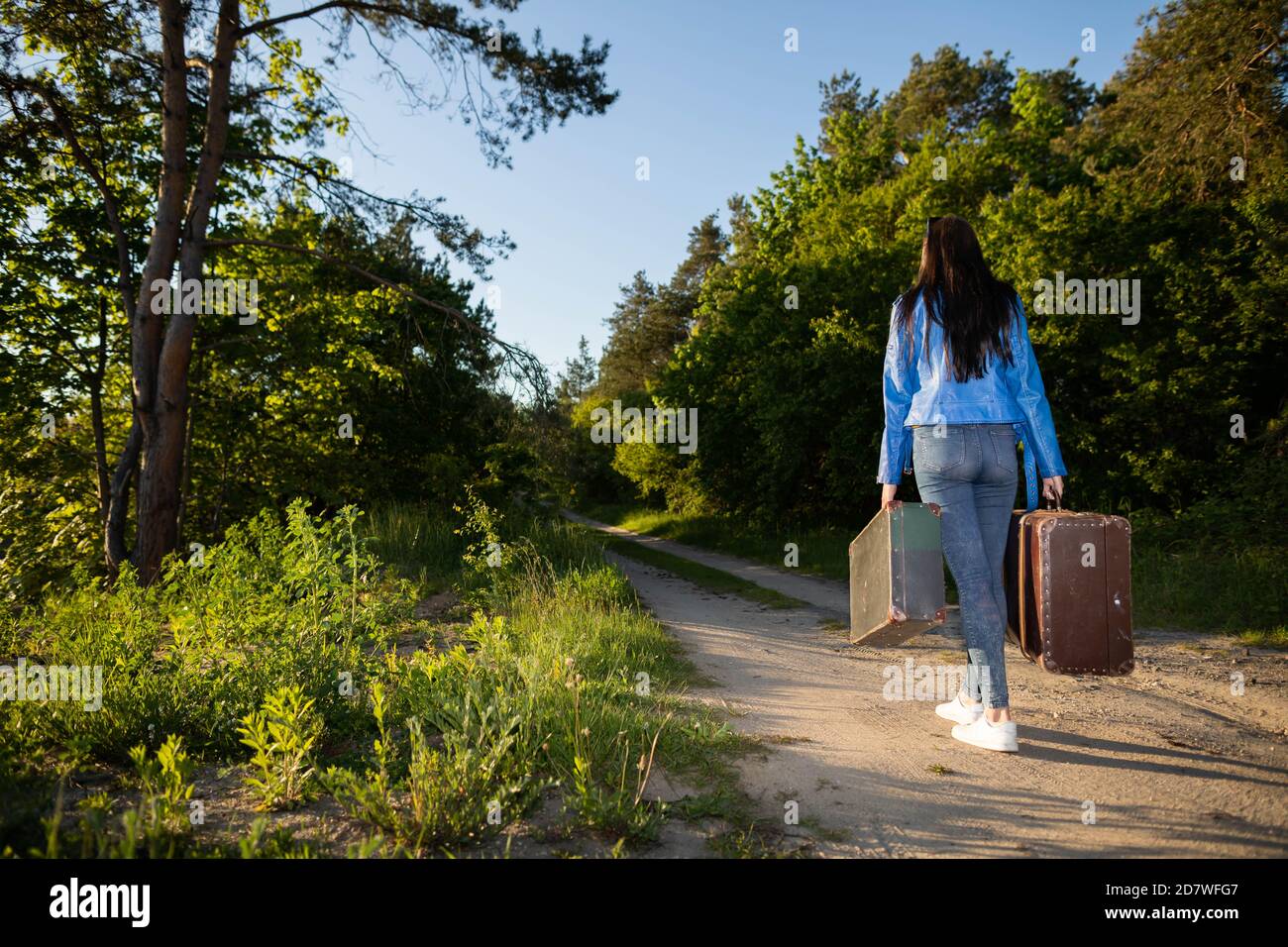 Returning home after a long trip. Rural unpaved road. Leafy green trees ...