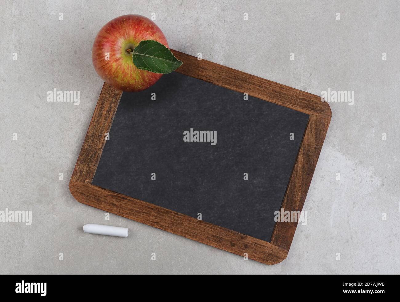 A vintage blank slate chalkboard with an apple on a grey mottled ...