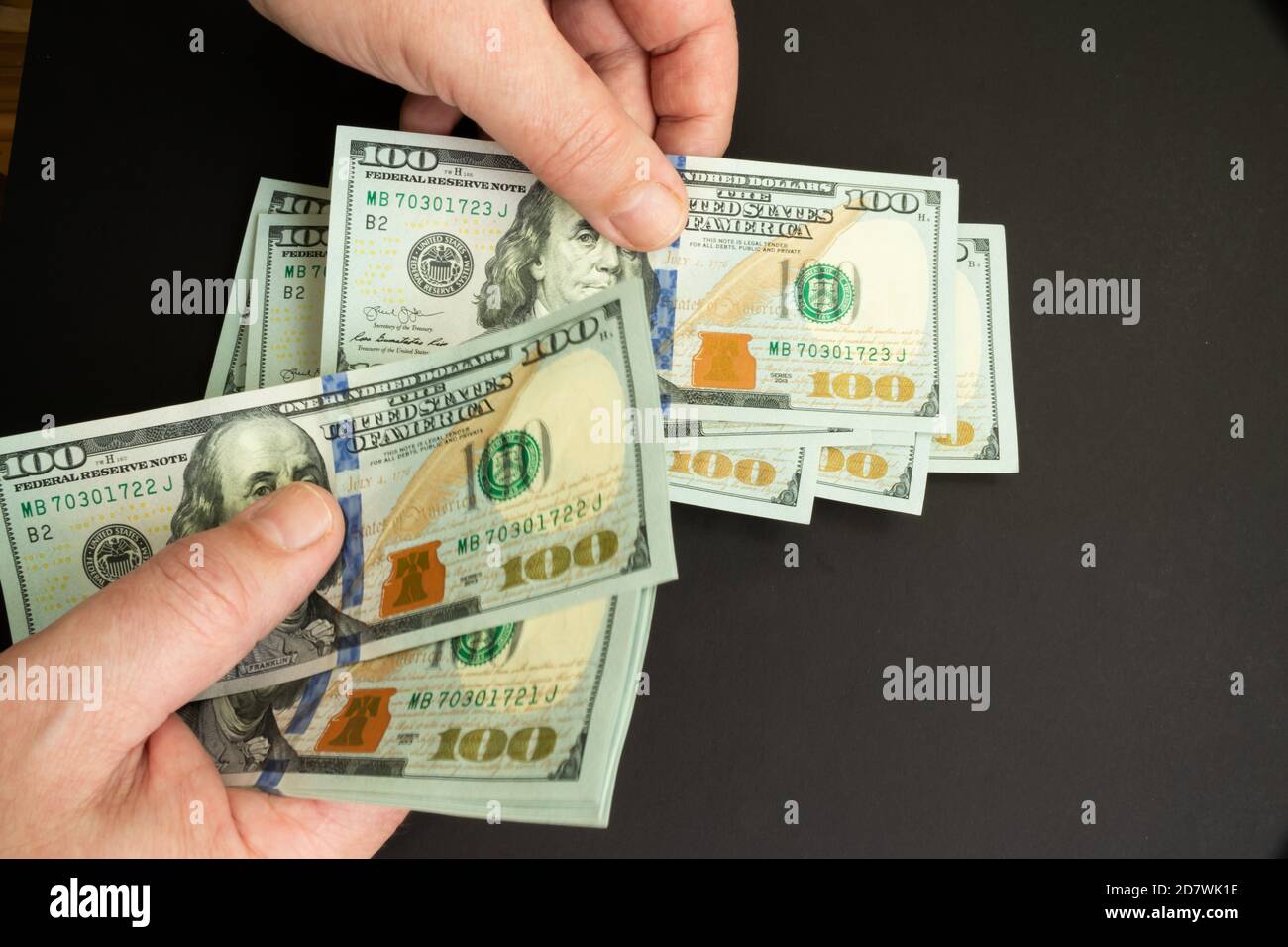Hands counting American 100 dollar bills on a black background Stock ...