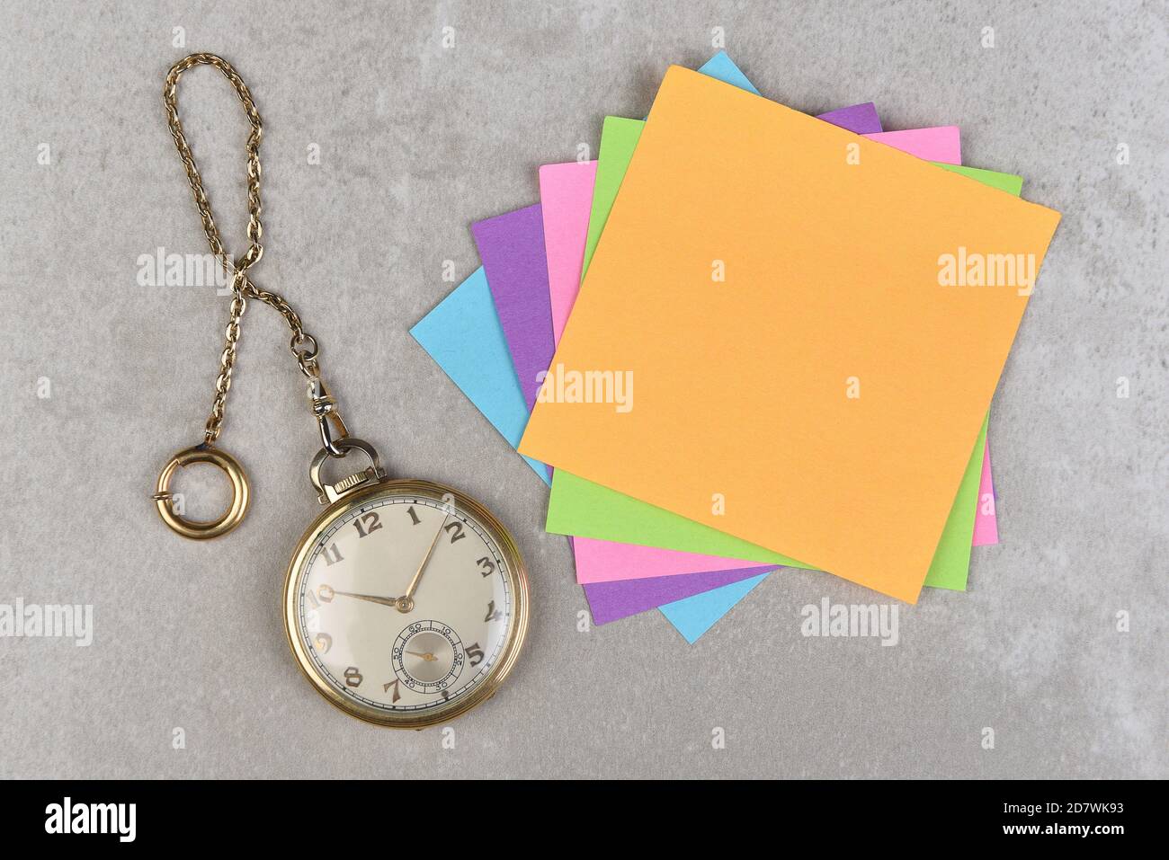 Flat lay still life of a gold pocket wach and a stack of blank sticky ...