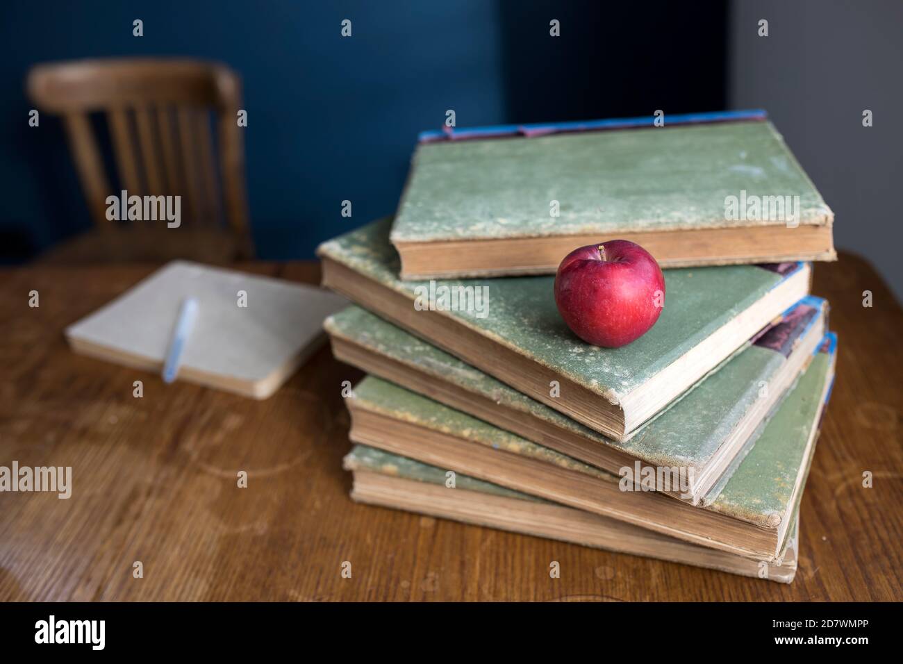 A stack of large, old, rag-bound books lie on a wooden table against a ...