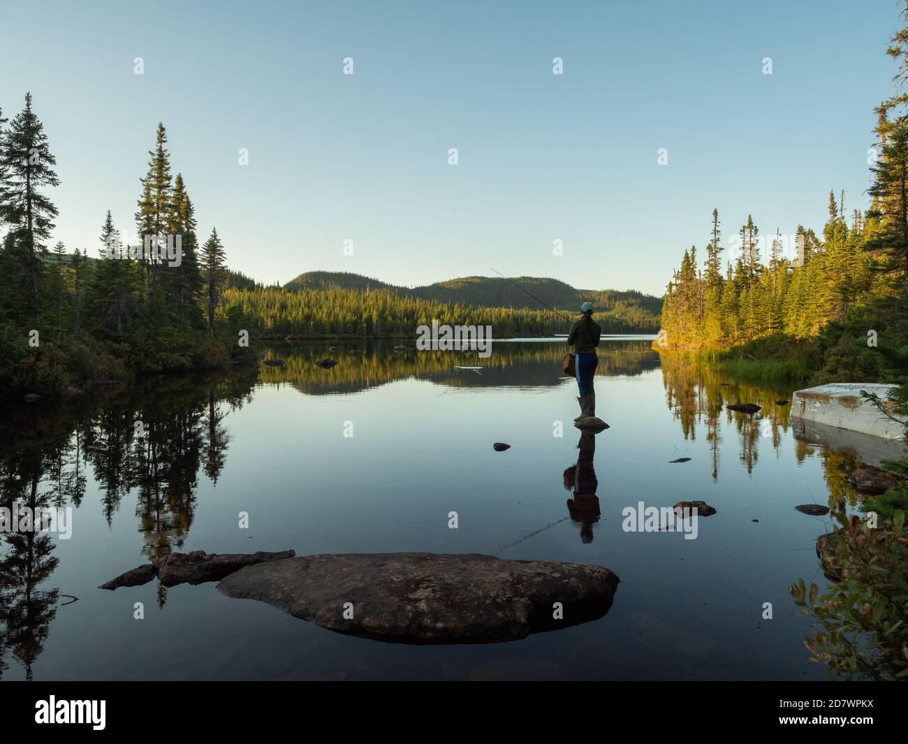 Woman standing on a rock, fishing in a lake in Northern Quebec Stock ...