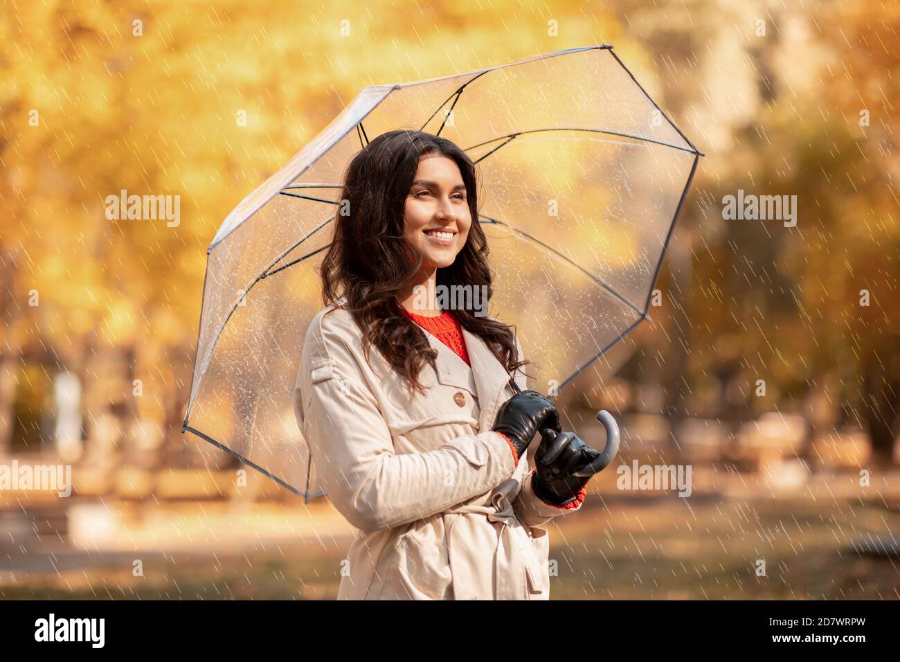 Change of season concept. Dreamy millennial woman using umbrella during ...