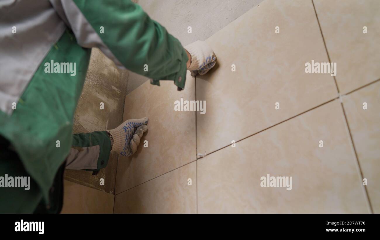 The master puts the tiles in the bathrooms.. Master in overalls puts ...