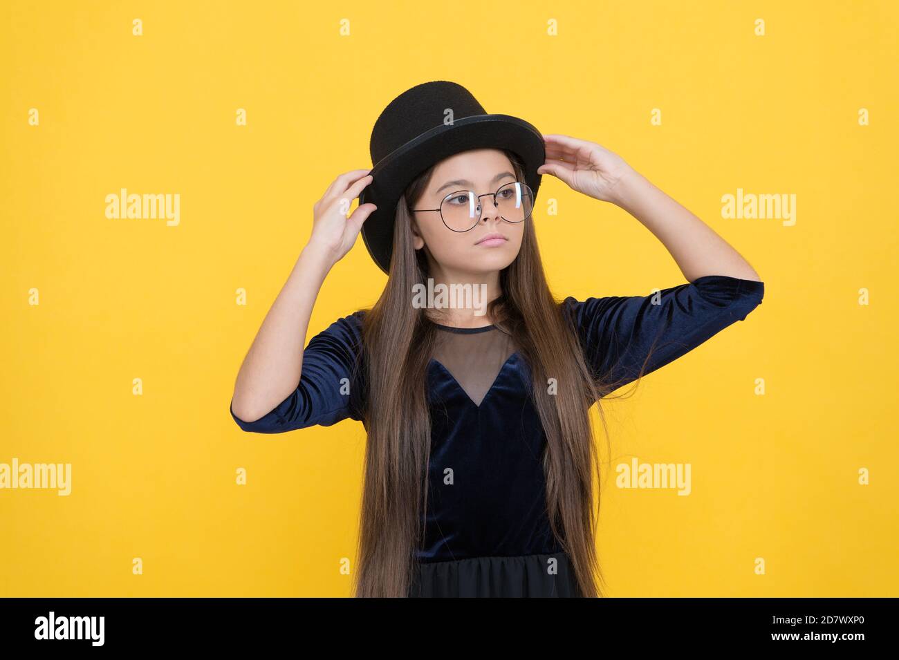 Little kid with long brunette hair fix black hat with fashion party ...