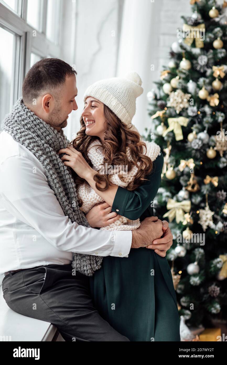 Celebrating Christmas together. Young couple in holiday clothes hugging ...