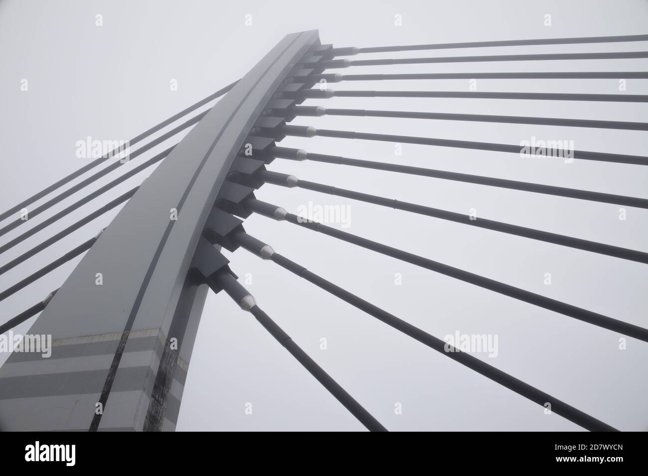 large steel arch of suspension bridge with metal ropes close up in fog ...