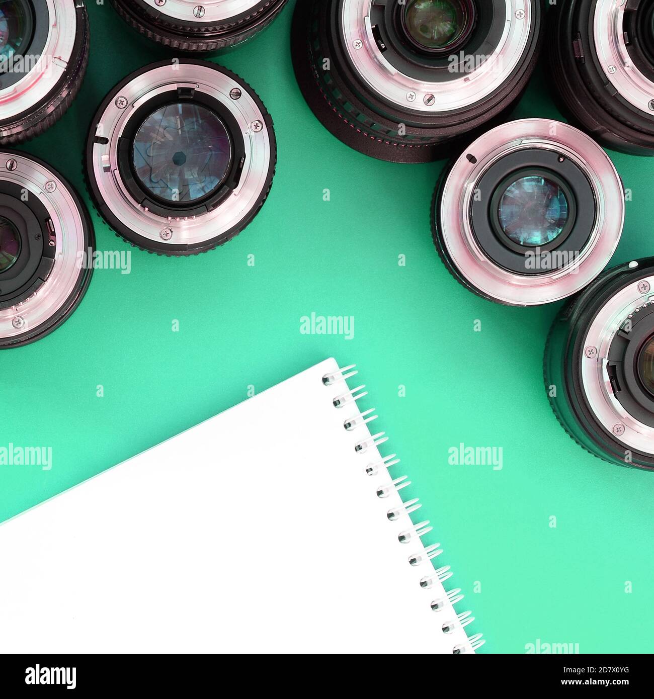 Several photographic lenses and white notebook lie on a bright ...