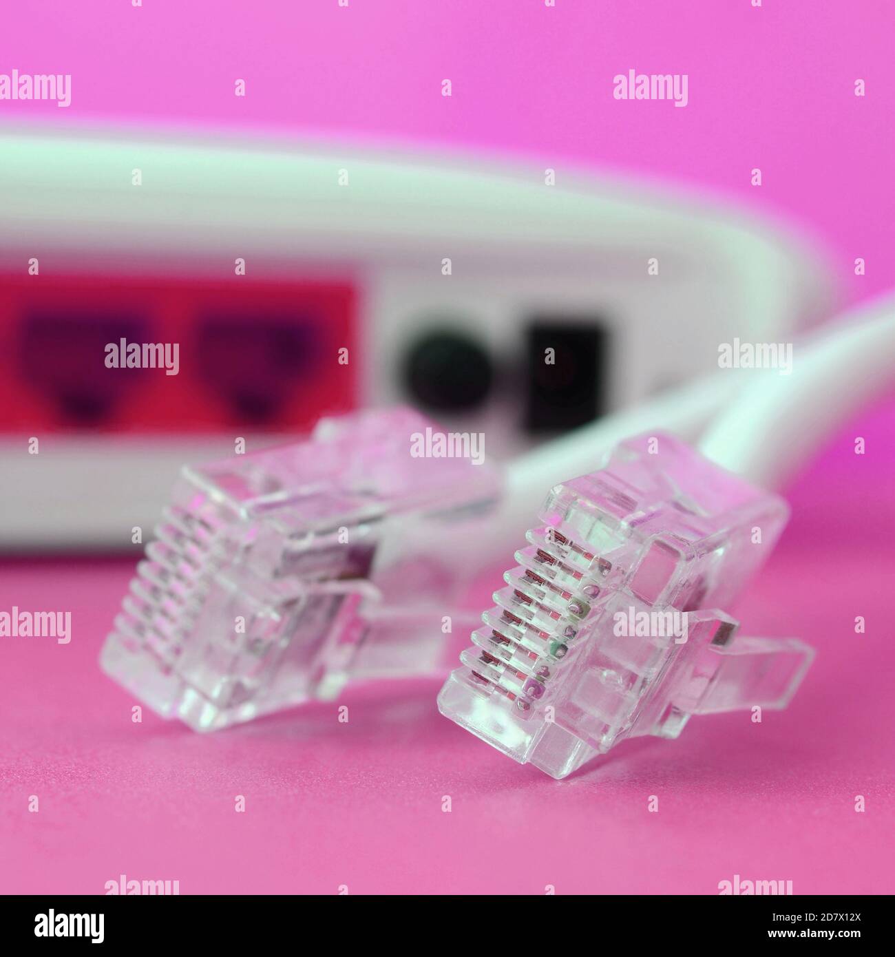 Internet router and Internet cable plugs lie on a bright pink ...
