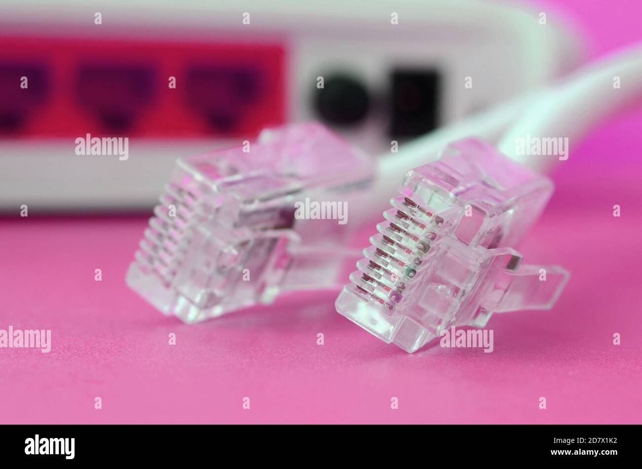Internet router and Internet cable plugs lie on a bright pink ...