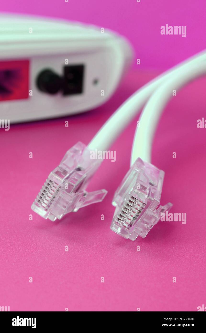 Internet router and Internet cable plugs lie on a bright pink ...