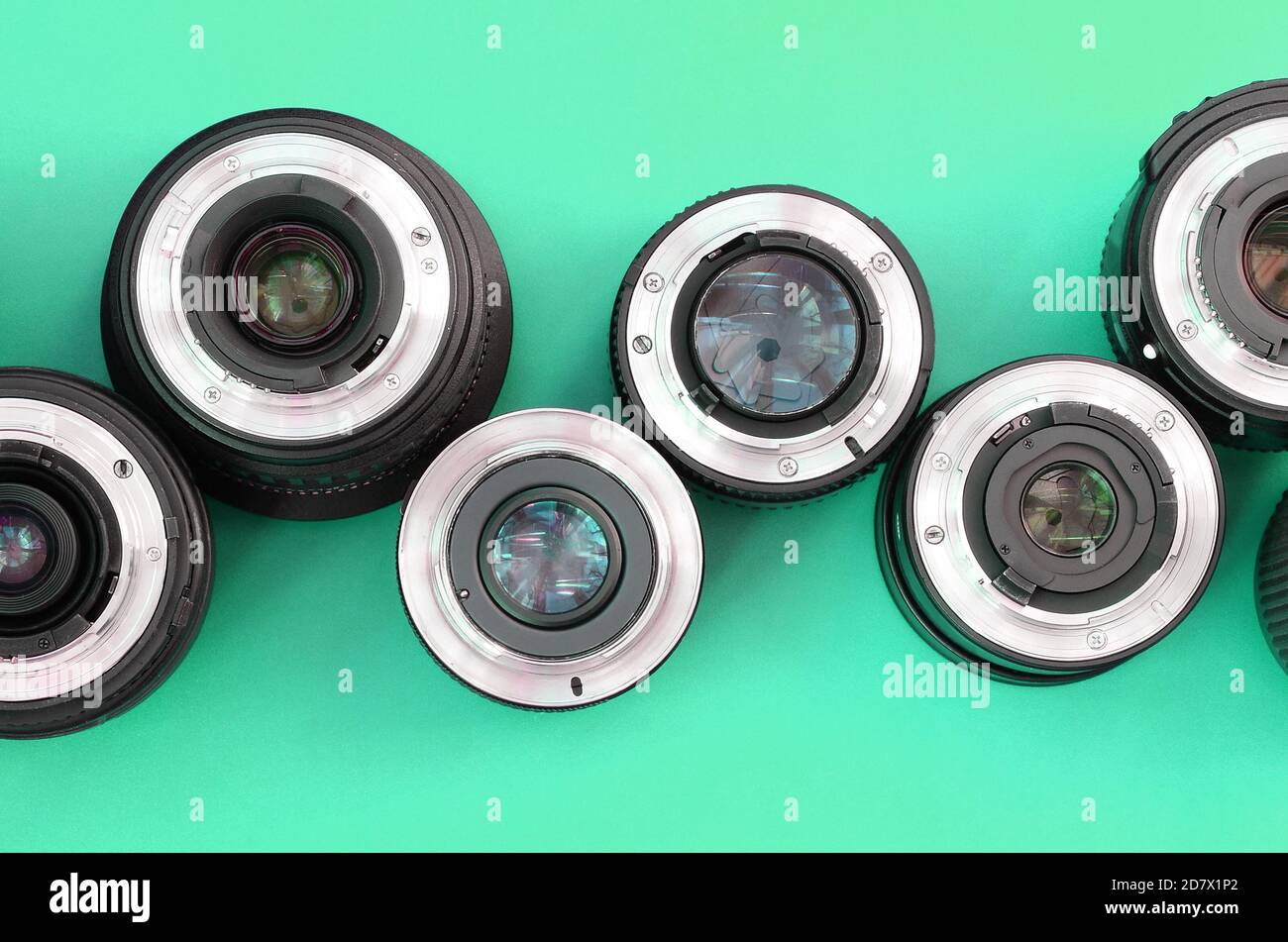 Several photographic lenses lie on a bright turquoise background. Space ...
