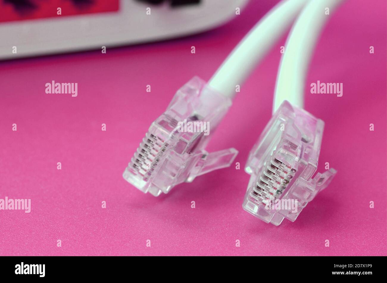Internet router and Internet cable plugs lie on a bright pink ...