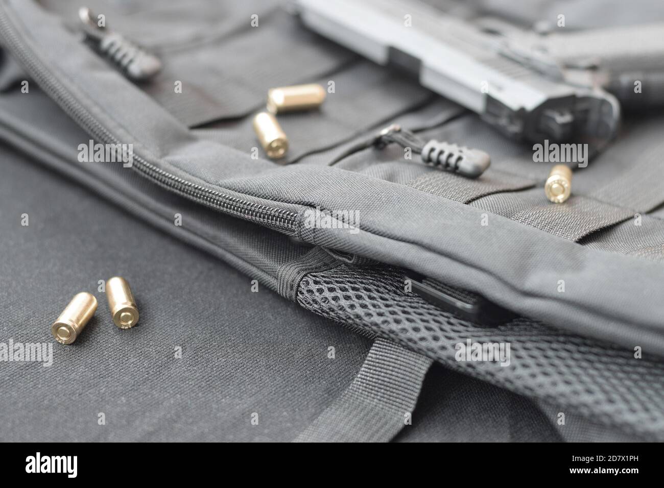 9mm bullets and pistol lie on a black tactical backpack. A set of ...