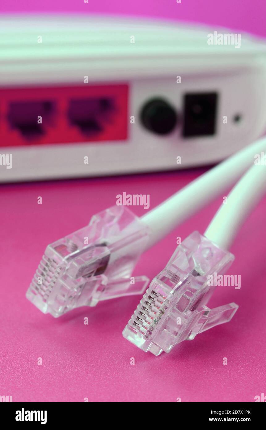 Internet router and Internet cable plugs lie on a bright pink ...
